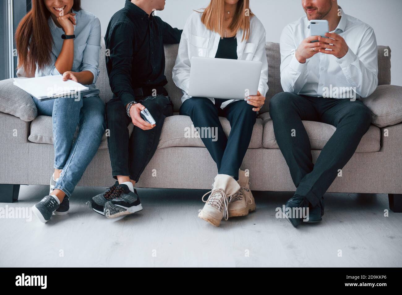 Group of friends sitting on the sofa with laptop and phones together ...