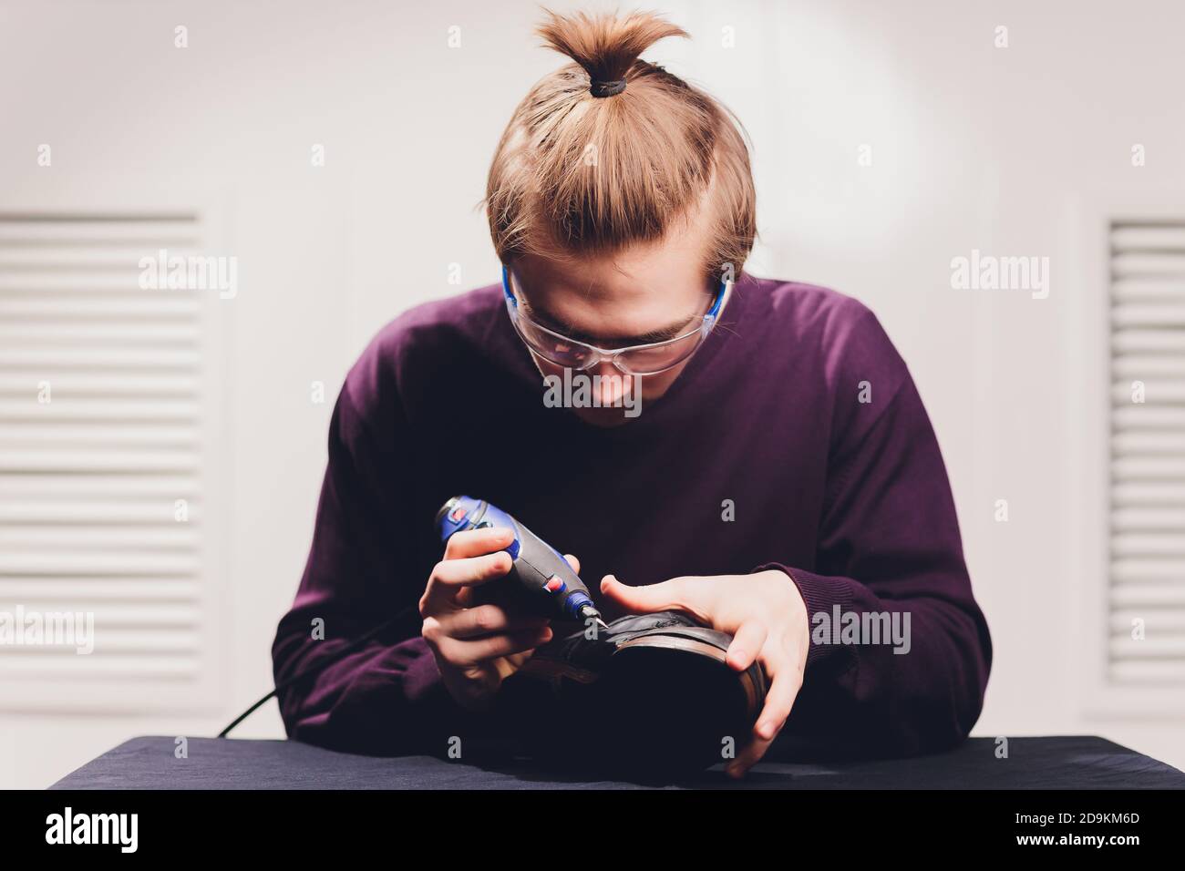 A shoemaker cuts the sole of a Shoe with a shoemaker's automatic cutter ...