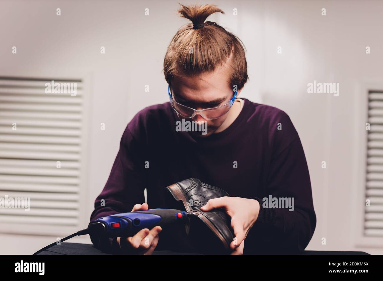 A shoemaker cuts the sole of a Shoe with a shoemaker's automatic cutter ...