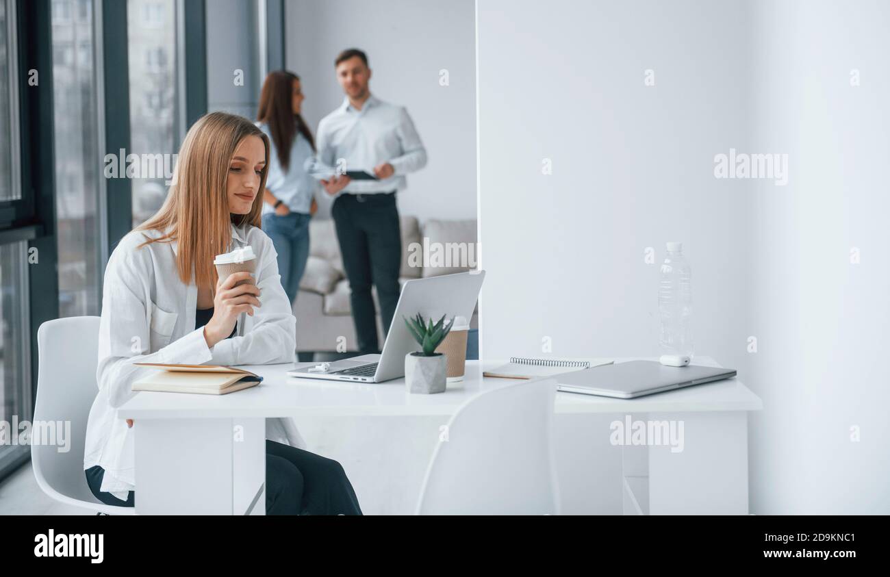 Woman with laptop sitting in front of group of young successful team ...