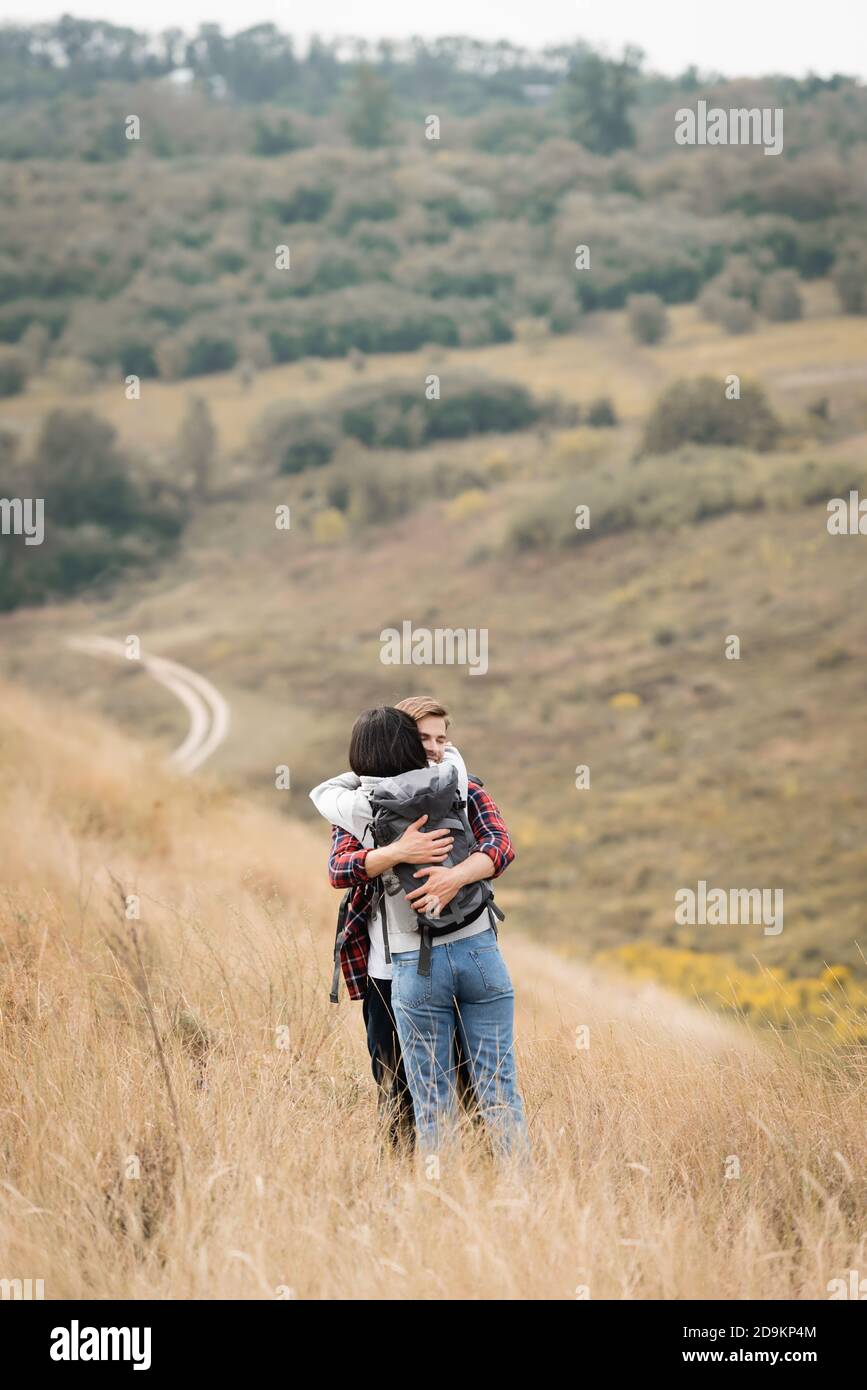 Young man hugging girlfriend with backpack during trip on hill Stock ...