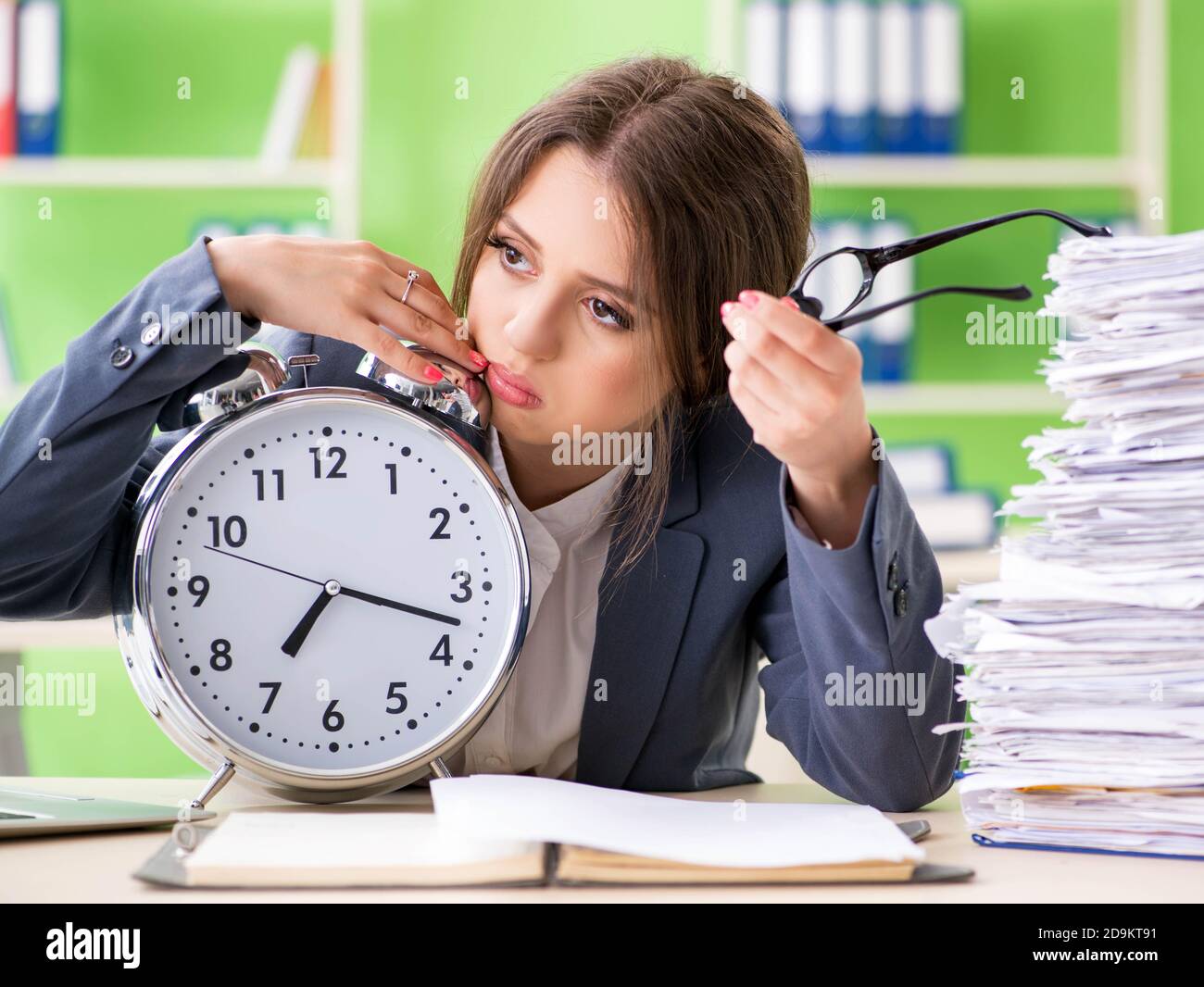The young female employee very busy with ongoing paperwork in time m ...