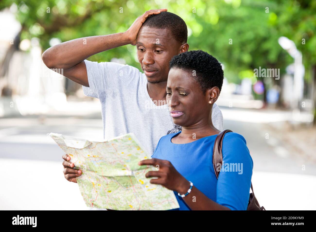 Young people standing in the street looking at geographical map with ...