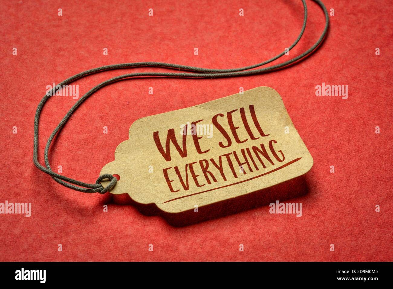 we sell everything sign a paper price tag against textured red paper ...