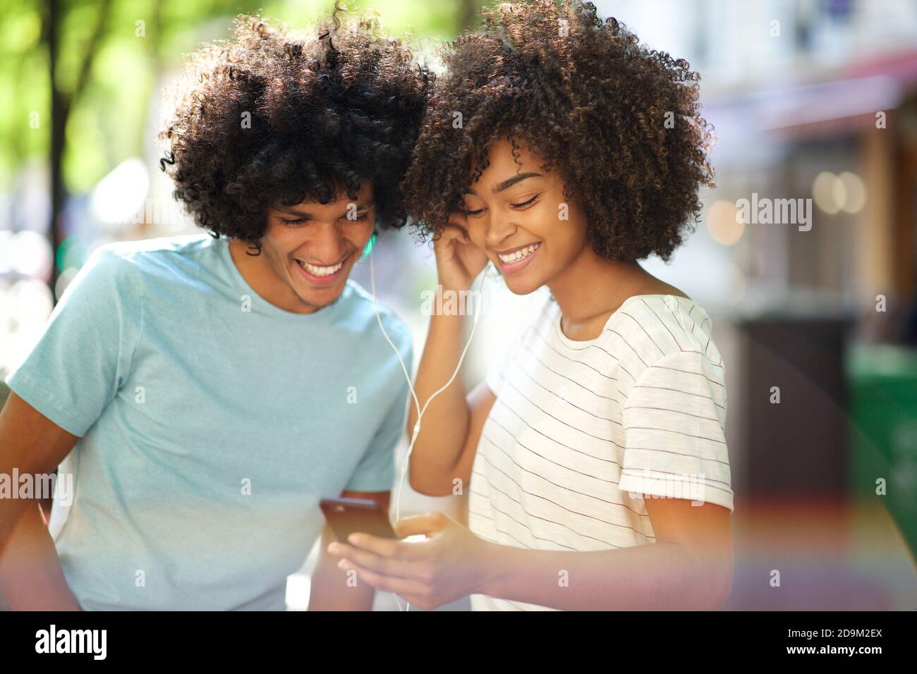 Portrait two friends listening to music with earphones and cellphone ...