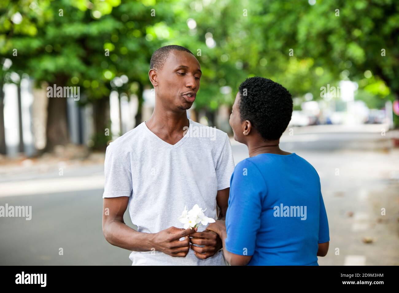 Young people standing face to face talking to each other smiling Stock ...