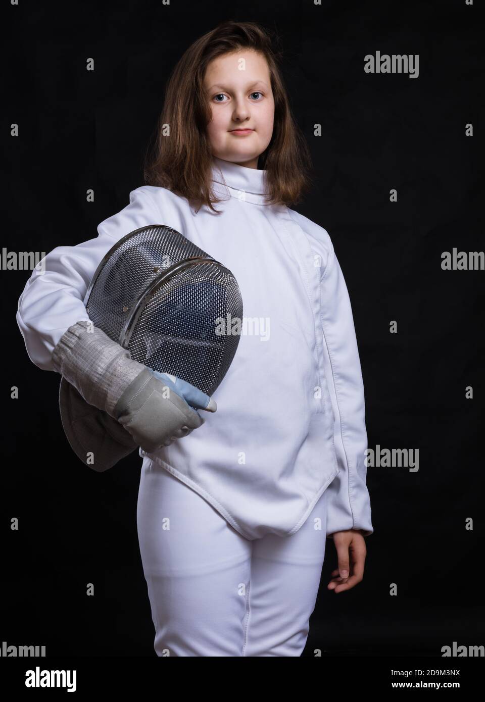 Teenage girl fencer dressed in uniform with epee and helmet studio ...