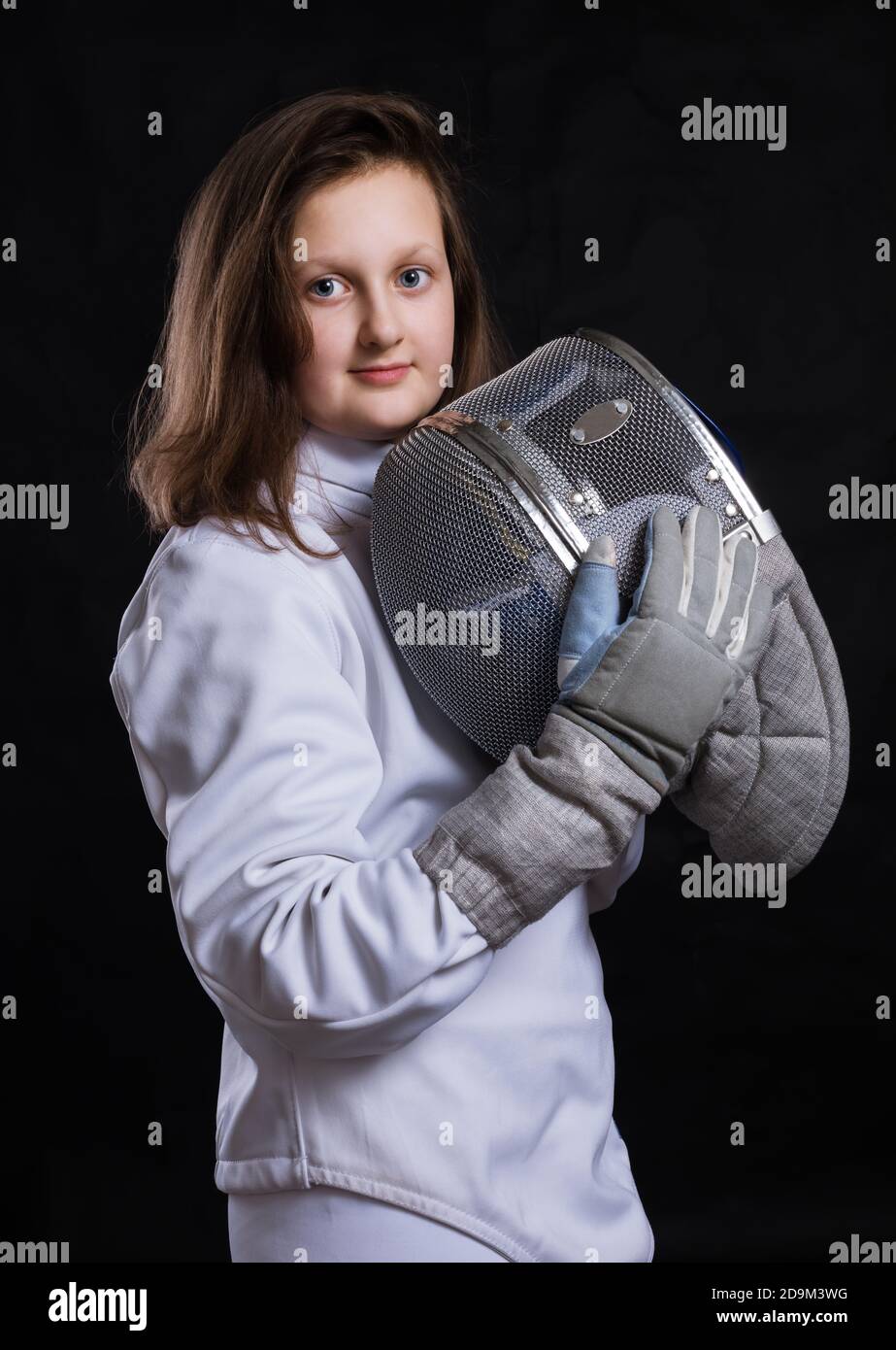 Teenage girl fencer dressed in uniform with epee and helmet studio ...