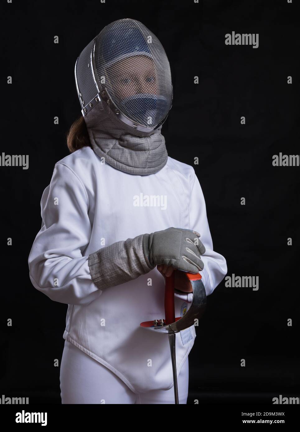 Teenage girl fencer dressed in uniform with epee and helmet studio ...