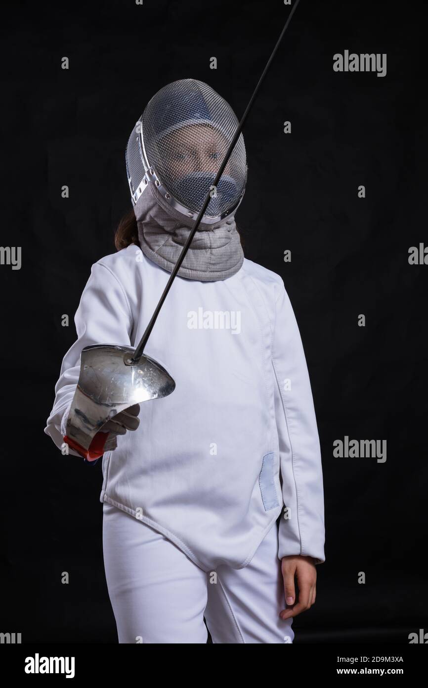 Teenage girl fencer dressed in uniform with epee and helmet studio ...