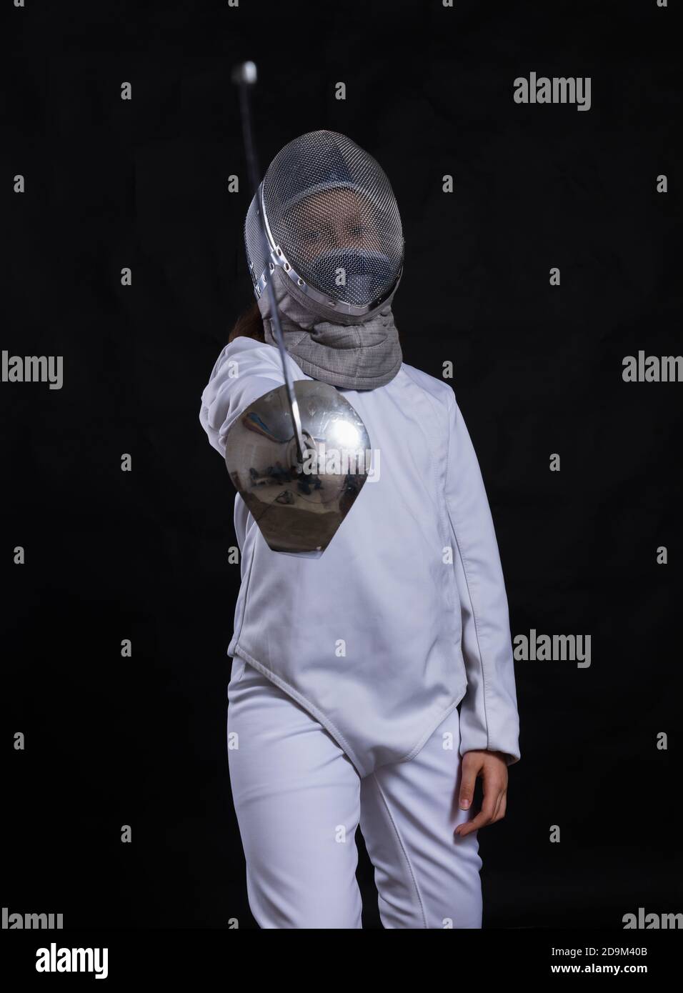 Teenage girl fencer dressed in uniform with epee and helmet studio ...
