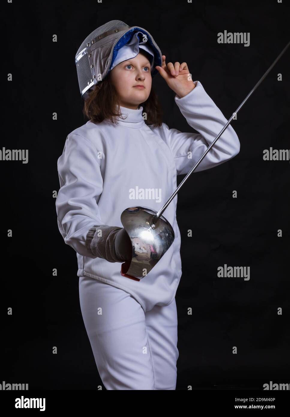 Teenage girl fencer dressed in uniform with epee and helmet studio ...
