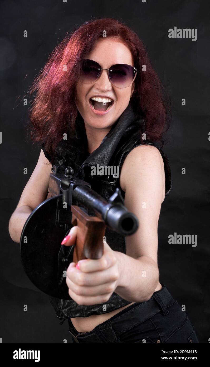 Beautiful woman dressed in black jacket with a gun studio portrait ...