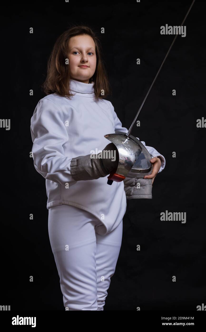 Teenage girl fencer dressed in uniform with epee and helmet studio ...