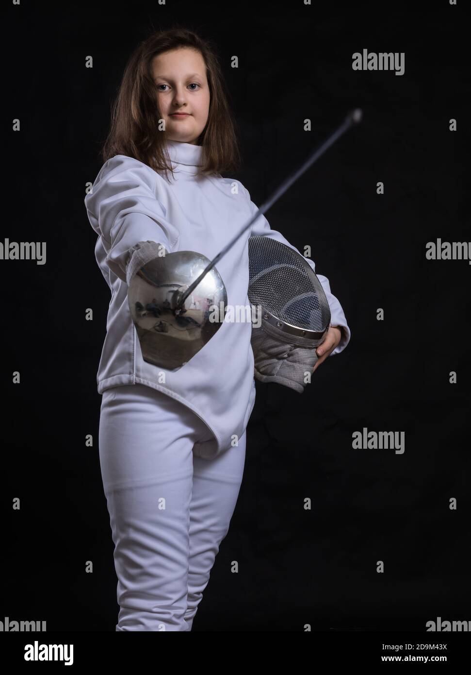 Teenage girl fencer dressed in uniform with epee and helmet studio ...
