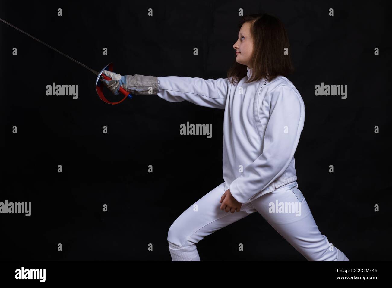 Teenage girl fencer dressed in uniform with epee and helmet studio ...