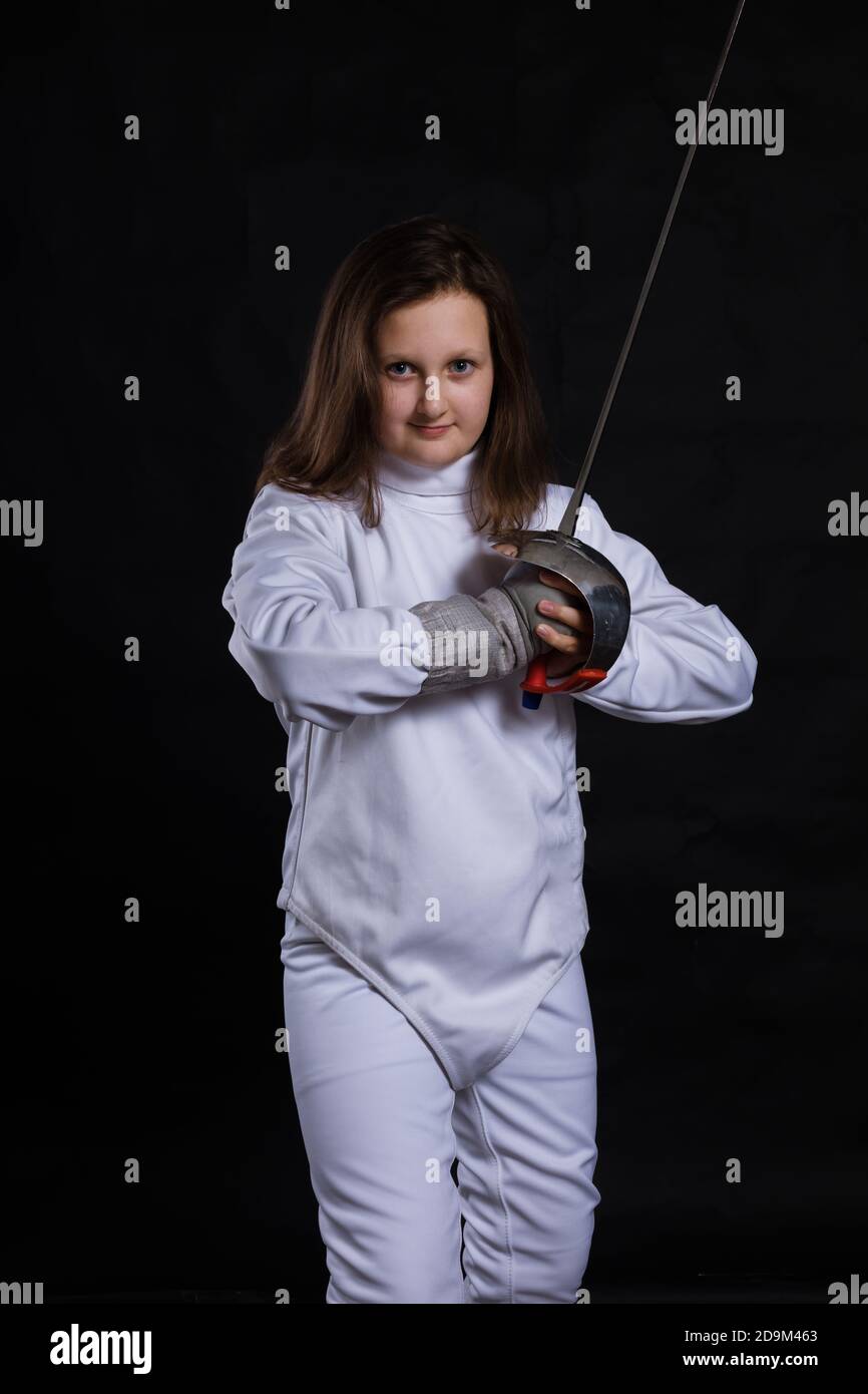 Teenage girl fencer dressed in uniform with epee and helmet studio ...
