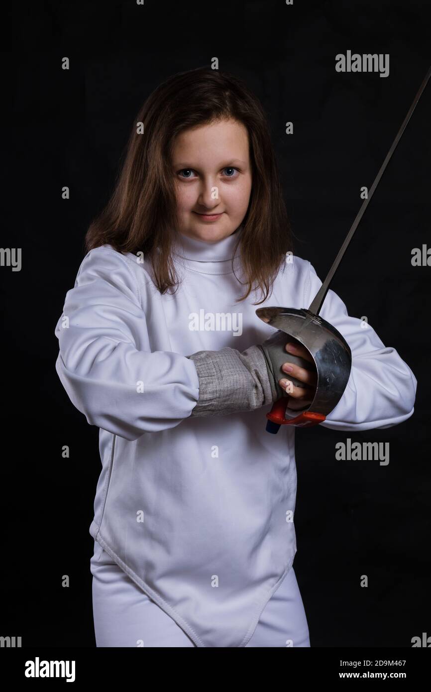 Teenage girl fencer dressed in uniform with epee and helmet studio ...