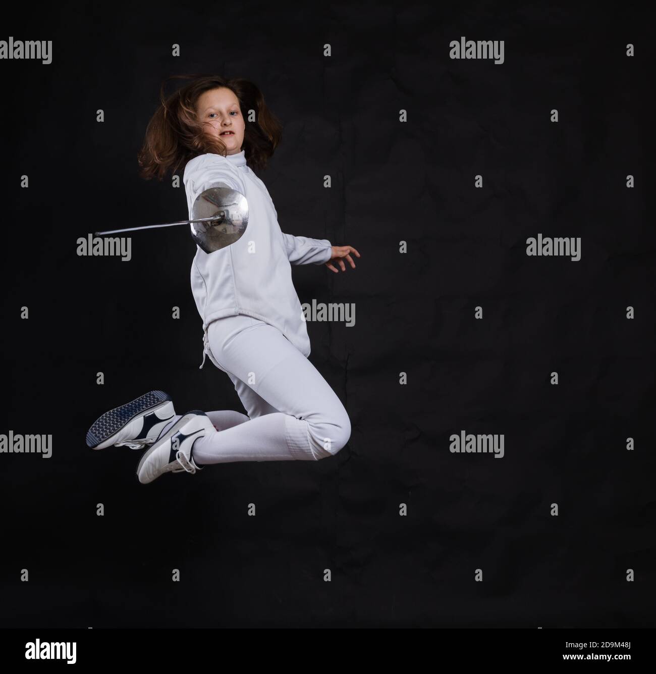 Teenage girl fencer dressed in uniform with epee and helmet studio ...