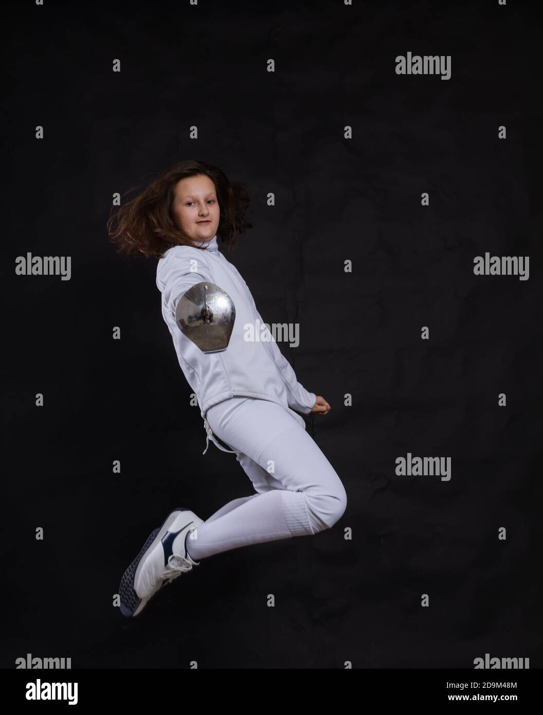 Teenage girl fencer dressed in uniform with epee and helmet studio ...