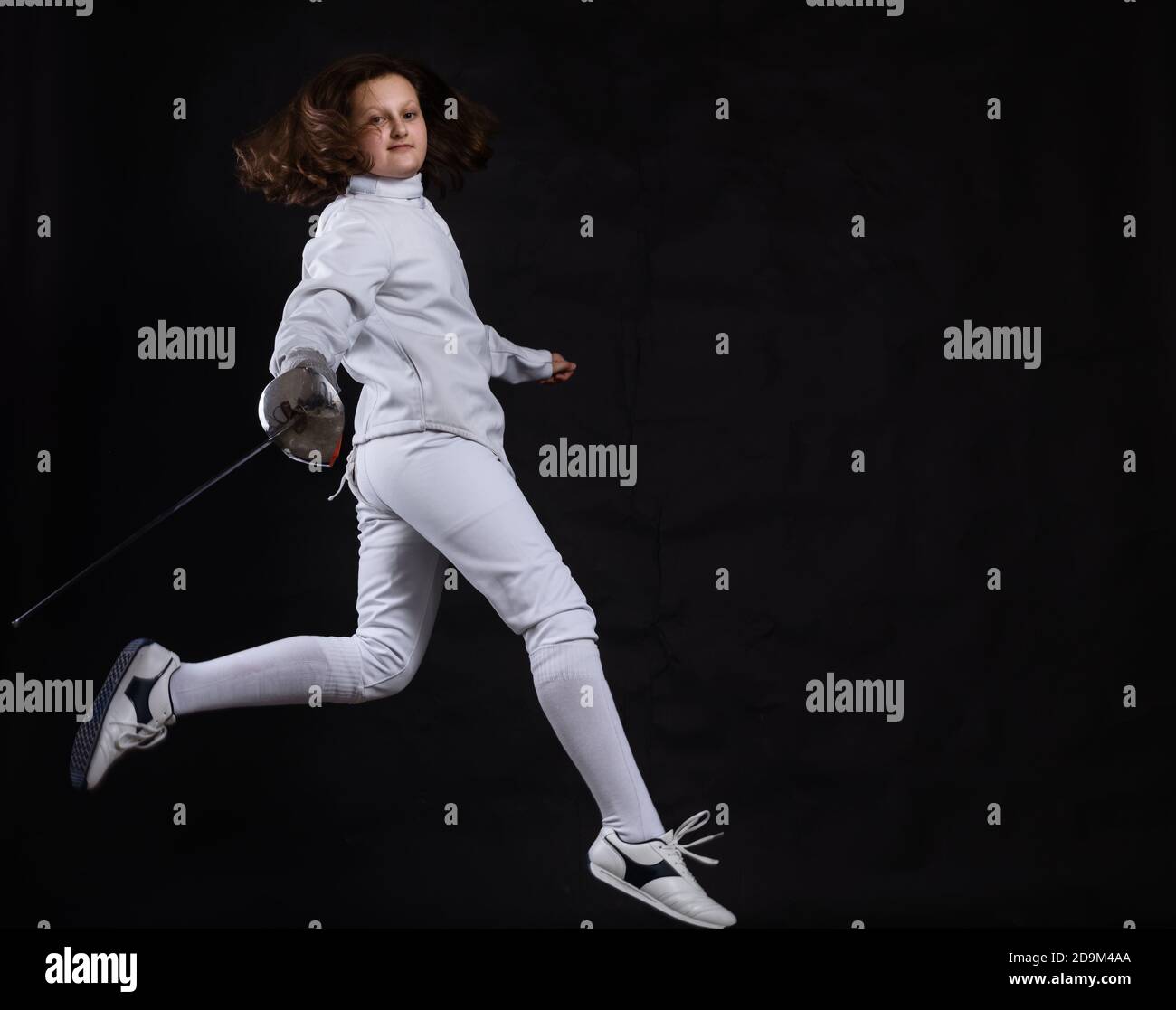 Teenage girl fencer dressed in uniform with epee and helmet studio ...