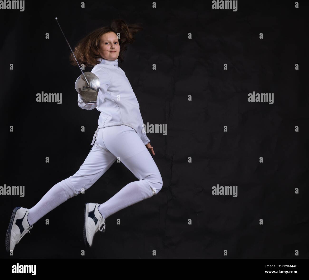 Teenage girl fencer dressed in uniform with epee and helmet studio ...