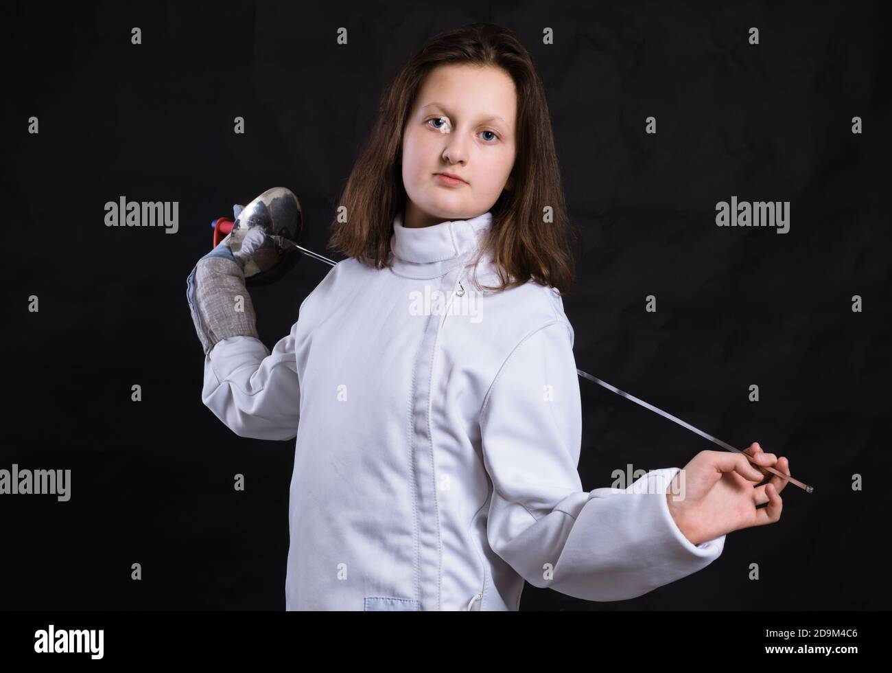 Teenage girl fencer dressed in uniform with epee and helmet studio ...