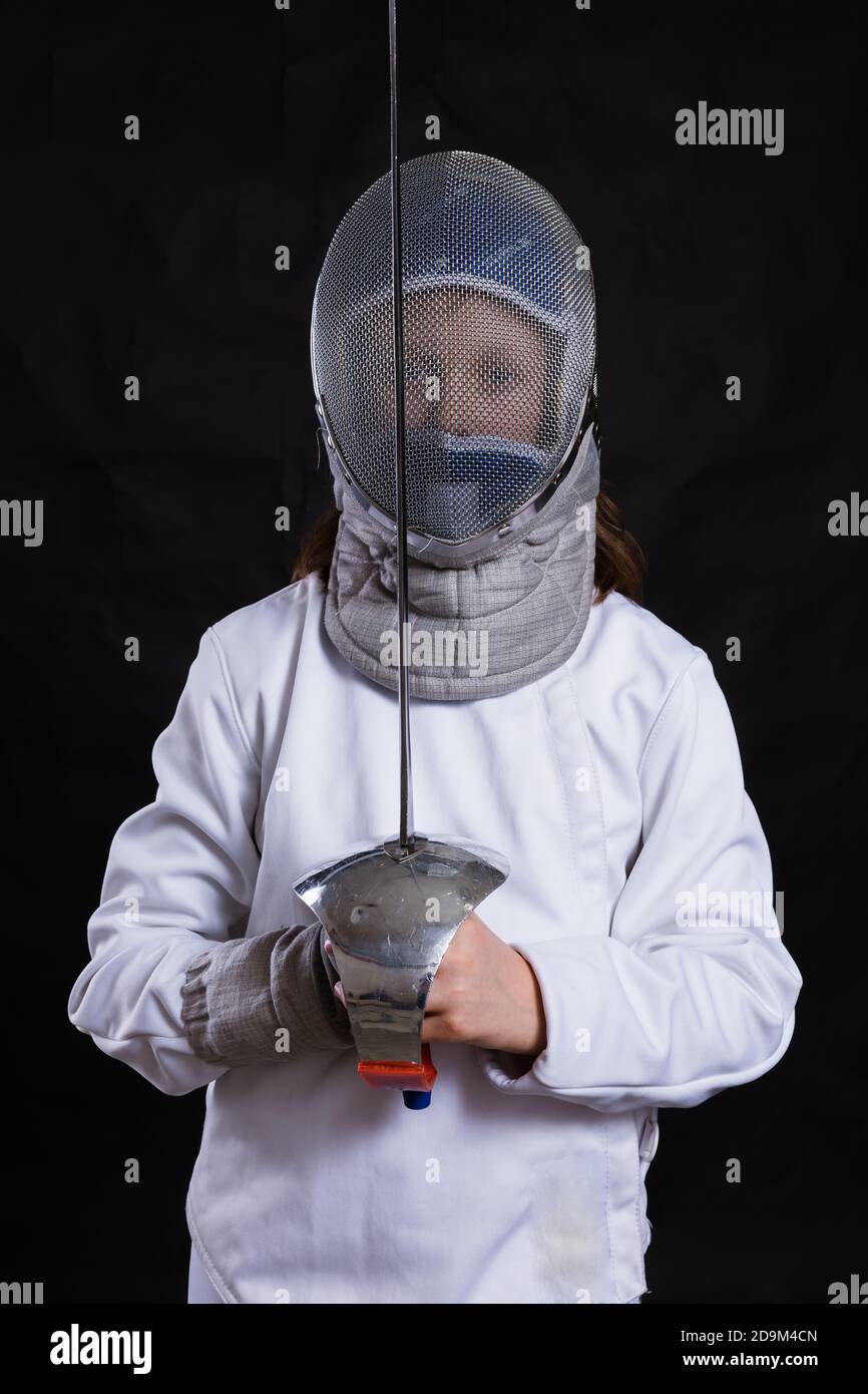 Teenage girl fencer dressed in uniform with epee and helmet studio ...