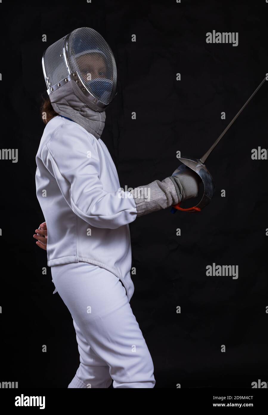 Teenage girl fencer dressed in uniform with epee and helmet studio ...