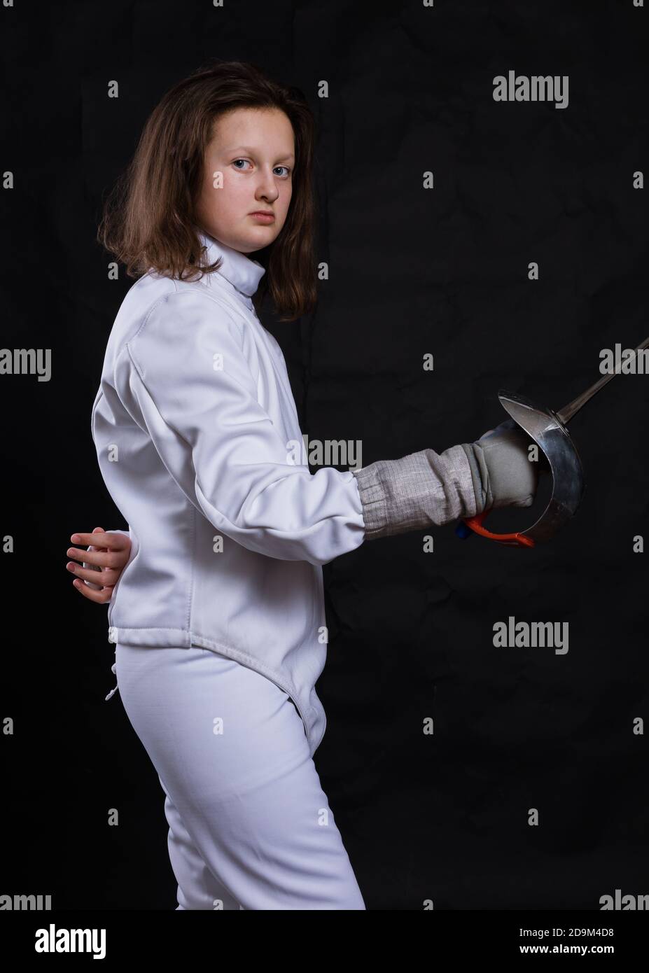 Teenage girl fencer dressed in uniform with epee and helmet studio ...