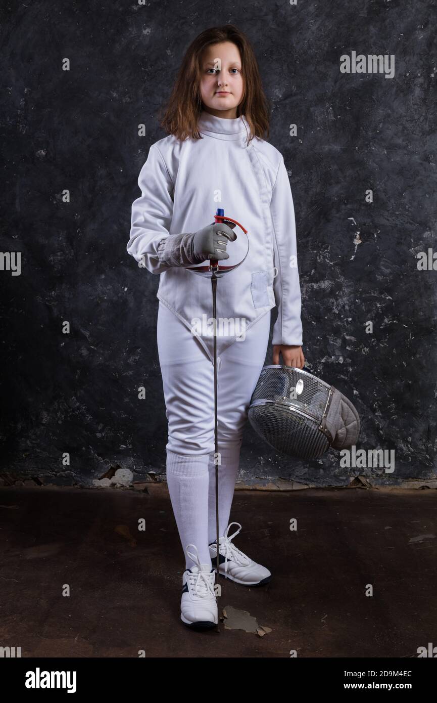 Teenage girl fencer dressed in uniform with epee and helmet studio ...