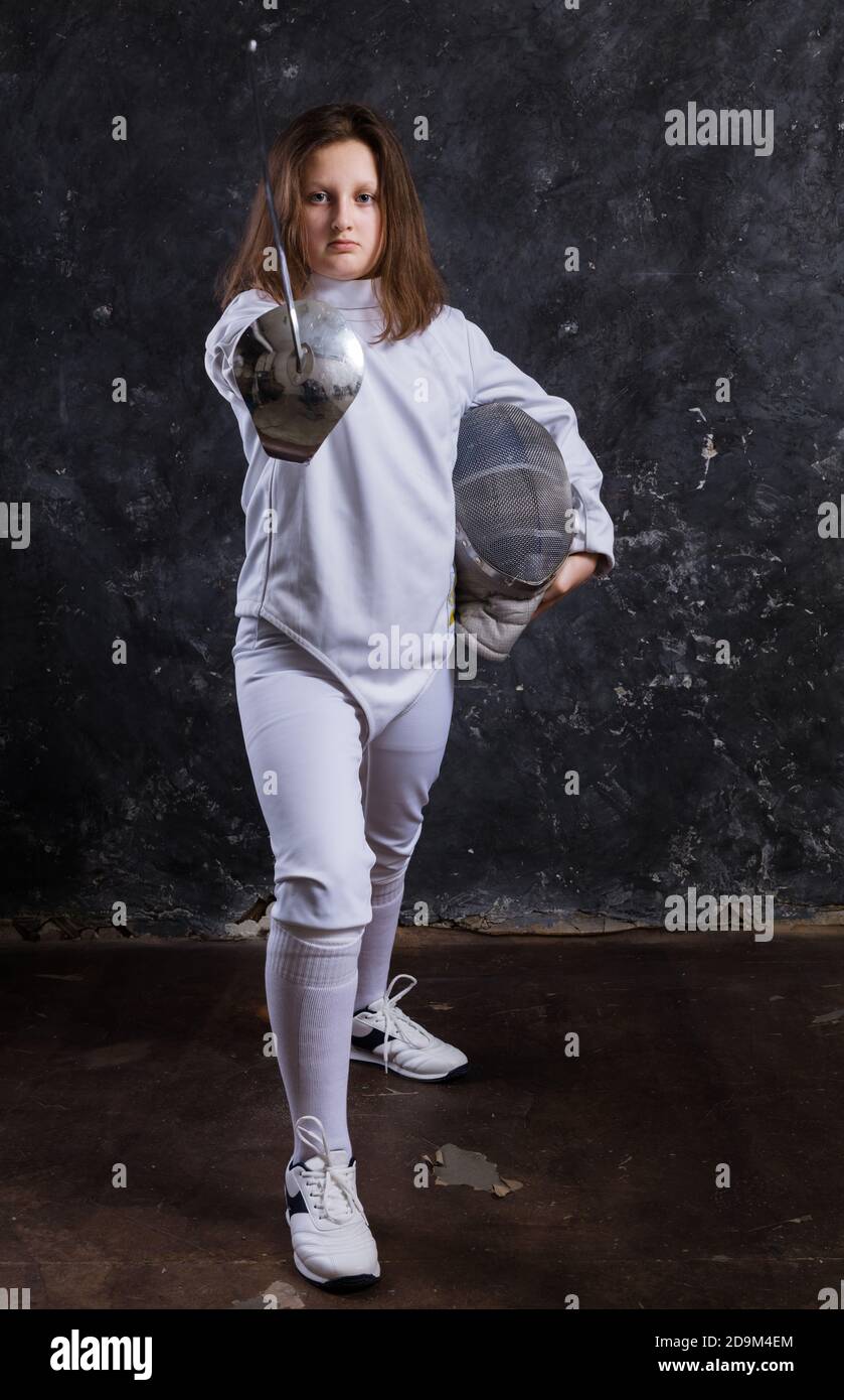 Teenage girl fencer dressed in uniform with epee and helmet studio ...