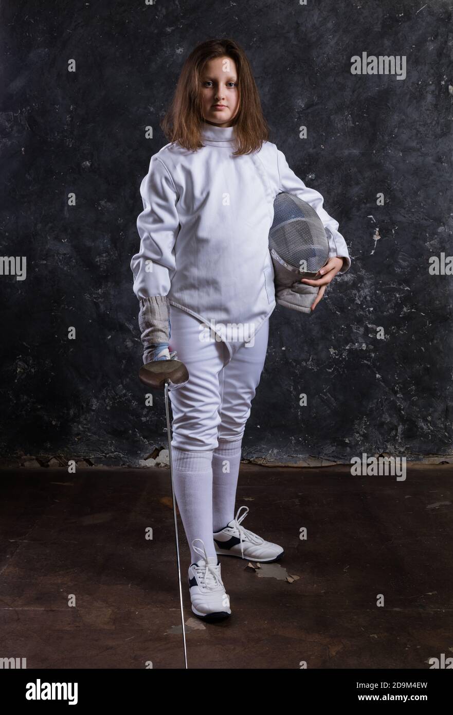 Teenage girl fencer dressed in uniform with epee and helmet studio ...