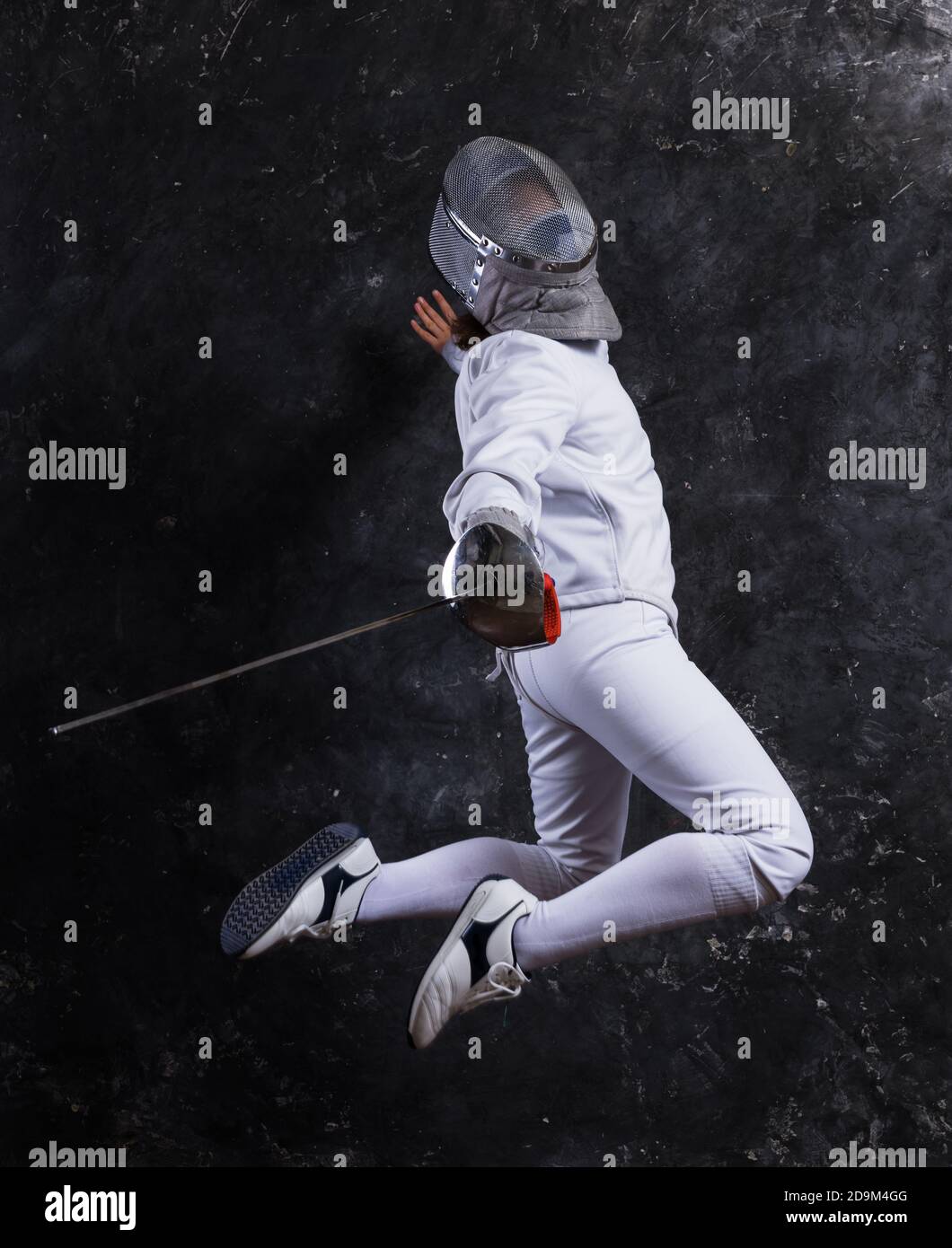 Teenage girl fencer dressed in uniform with epee and helmet studio ...