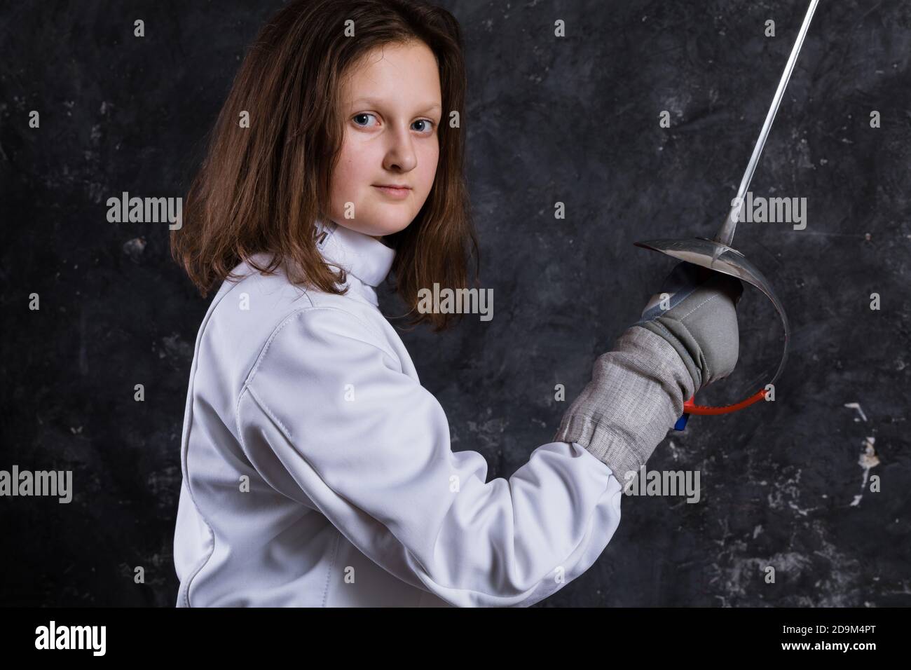 Teenage girl fencer dressed in uniform with epee and helmet studio ...
