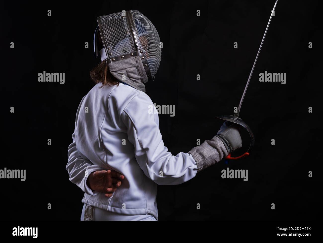 Teenage girl fencer dressed in uniform with epee and helmet studio ...