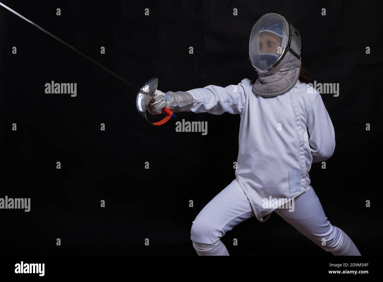 Teenage girl fencer dressed in uniform with epee and helmet studio ...