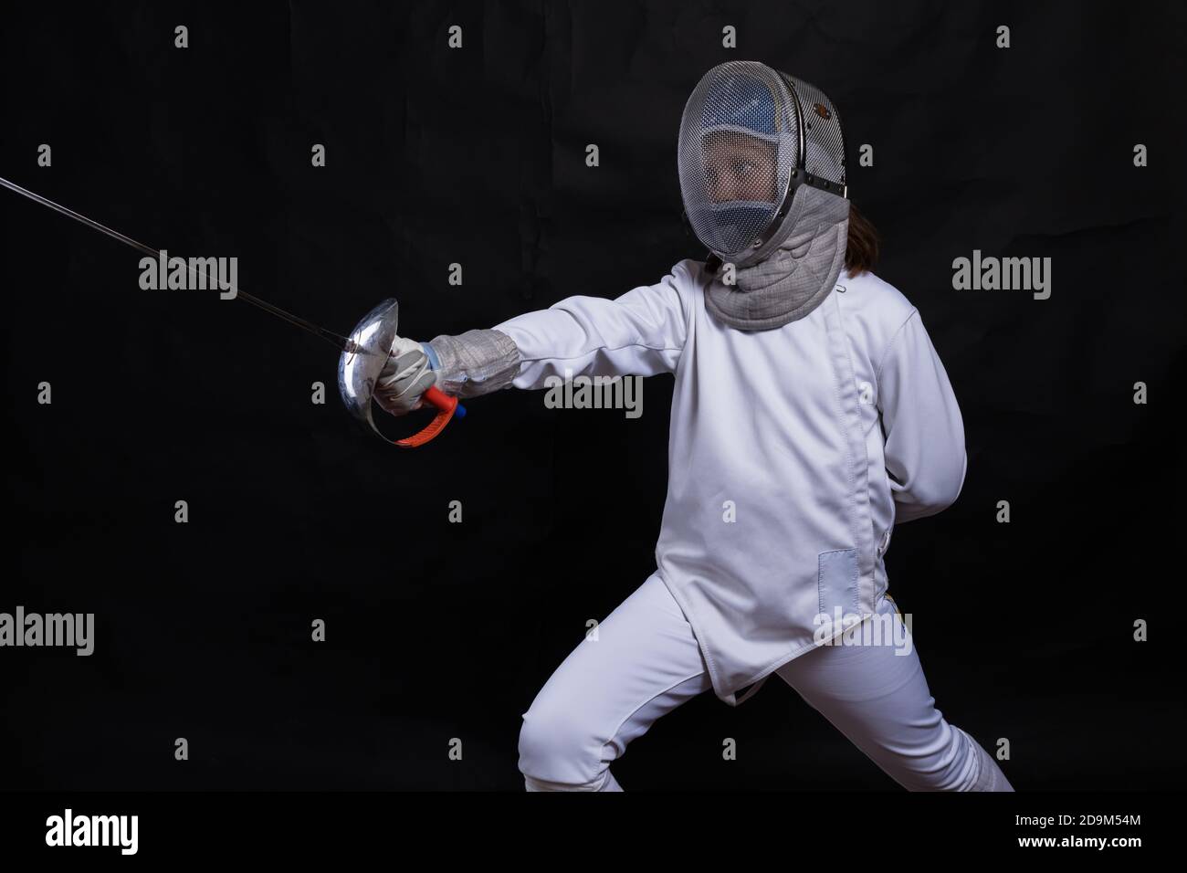 Teenage girl fencer dressed in uniform with epee and helmet studio ...