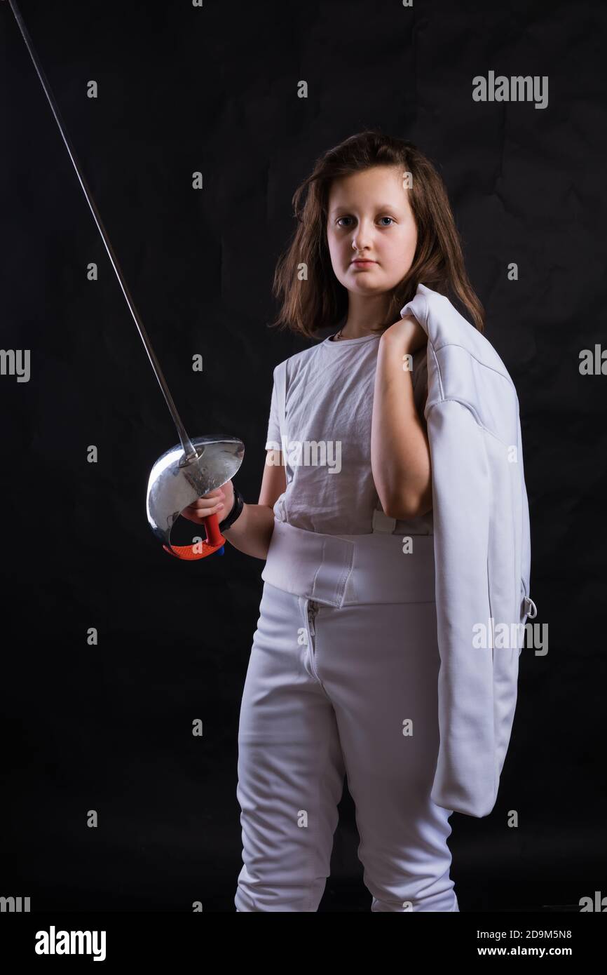 Teenage girl fencer dressed in uniform with epee and helmet studio ...
