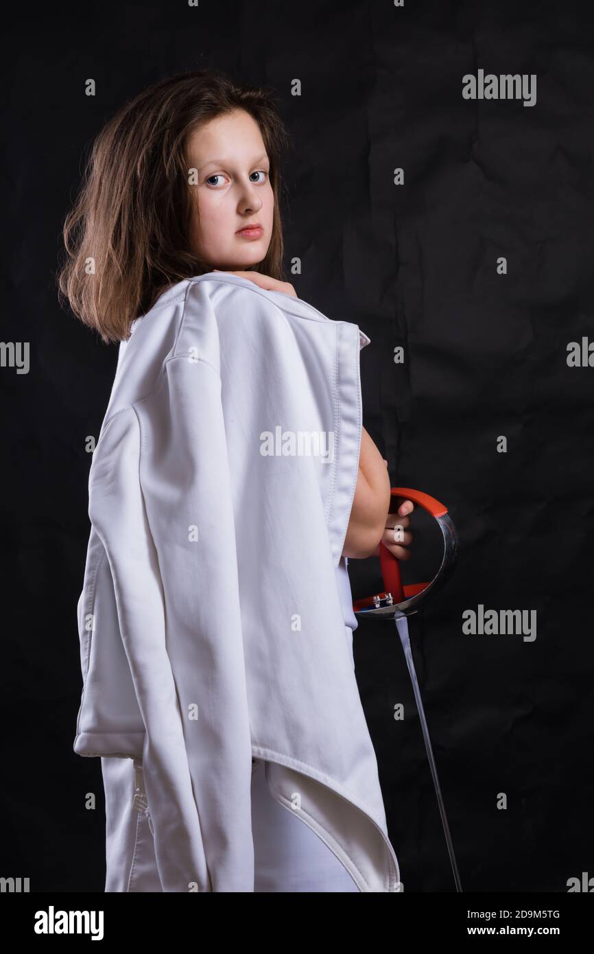 Teenage girl fencer dressed in uniform with epee and helmet studio ...