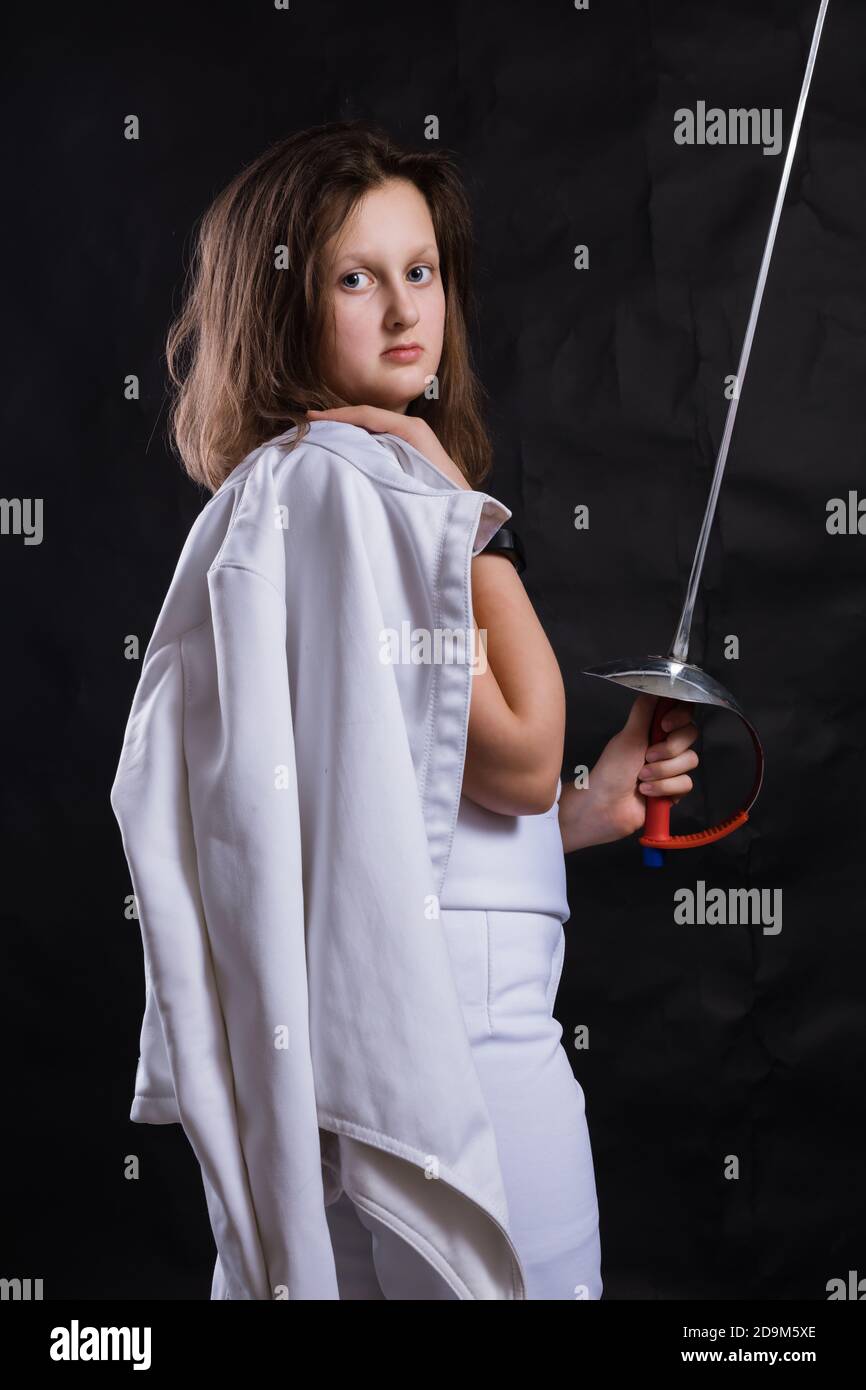 Teenage girl fencer dressed in uniform with epee and helmet studio ...