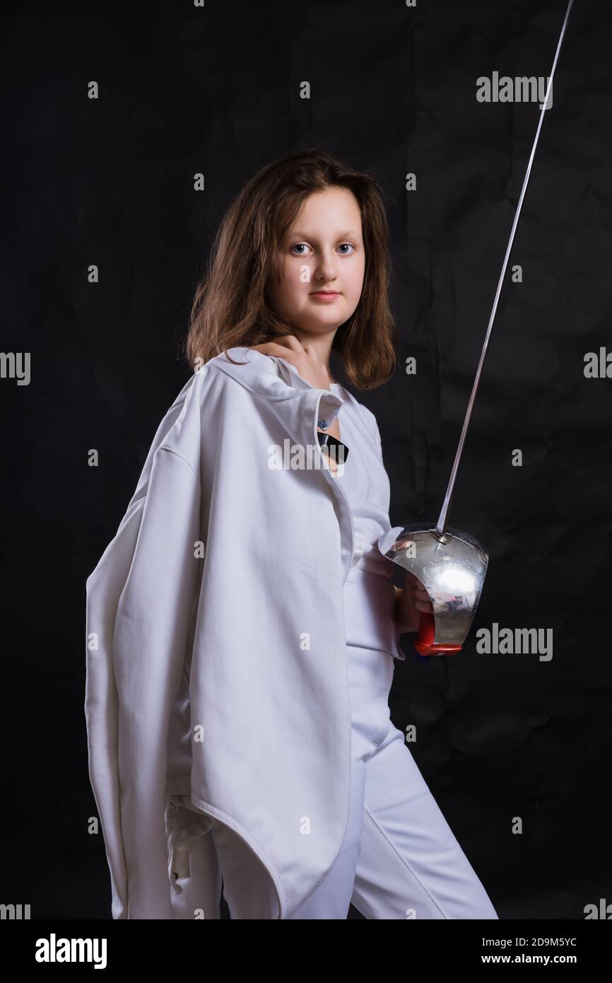 Teenage girl fencer dressed in uniform with epee and helmet studio ...