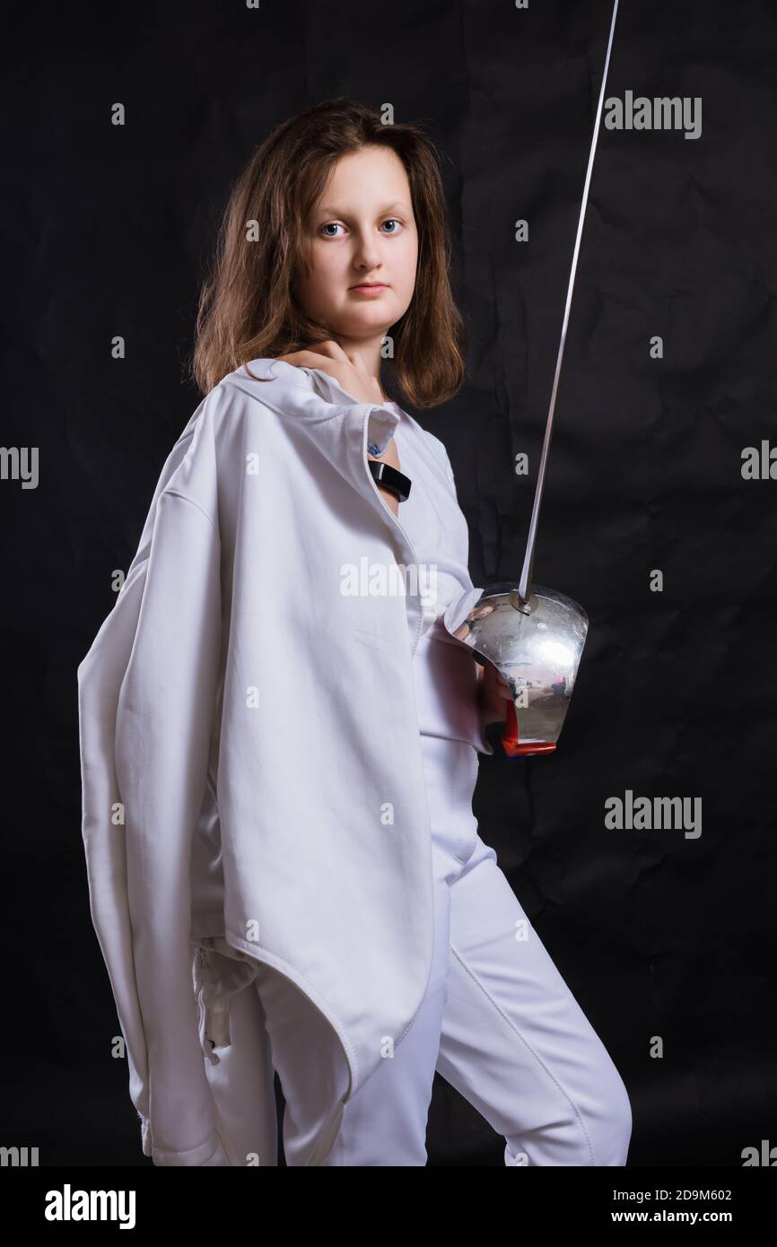 Teenage girl fencer dressed in uniform with epee and helmet studio ...