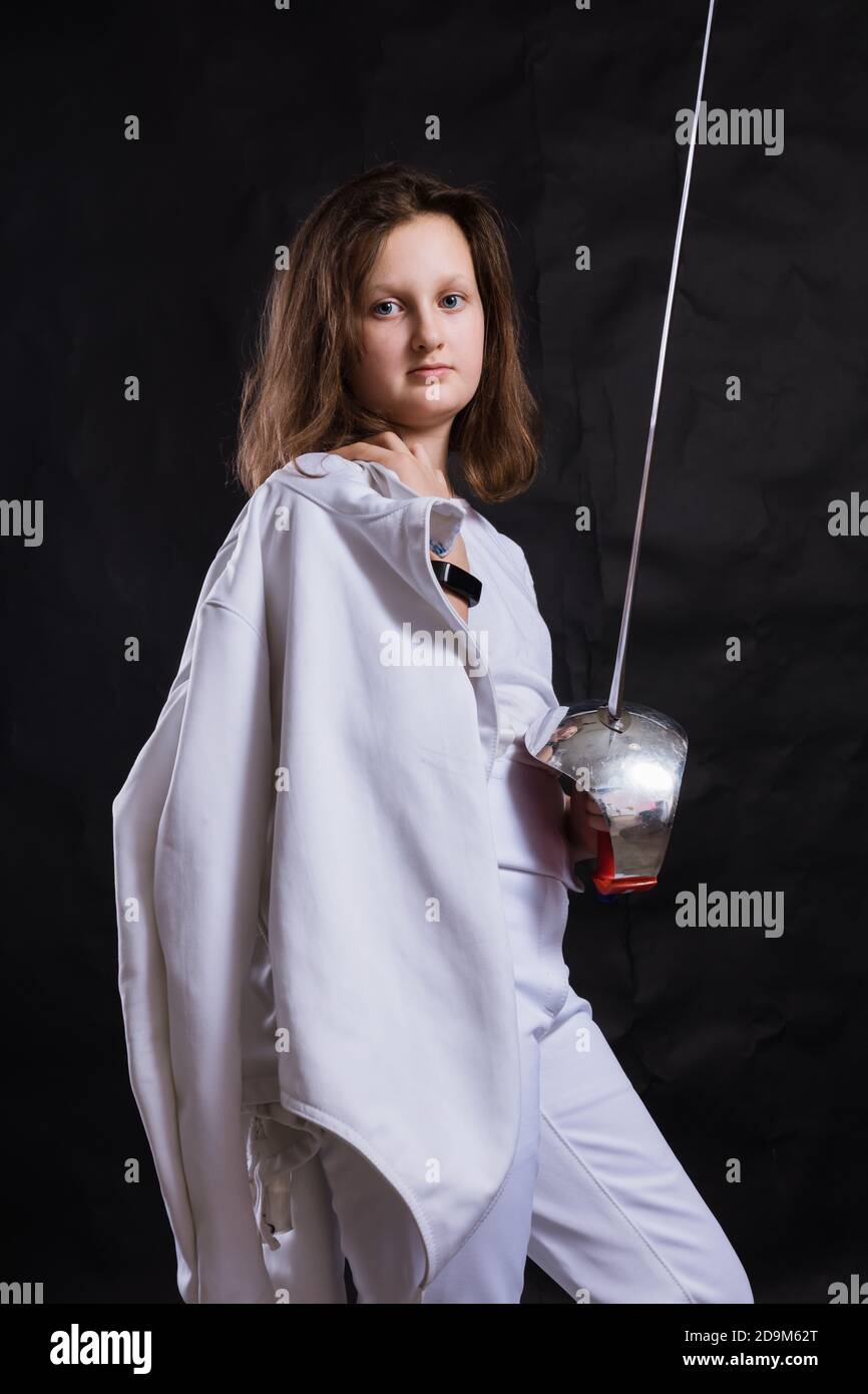 Teenage girl fencer dressed in uniform with epee and helmet studio ...