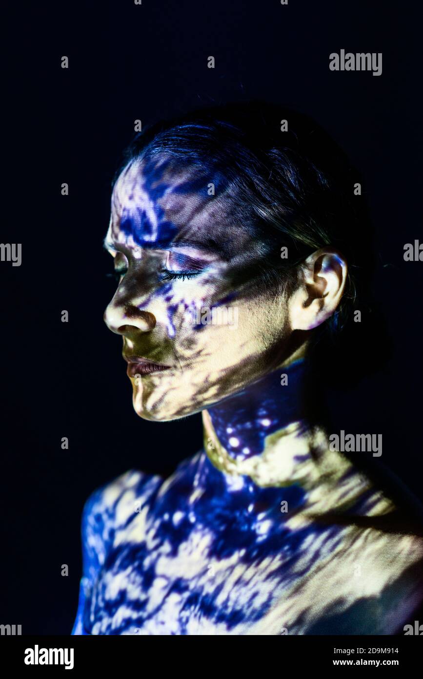 Creative portrait of a woman illuminated with colored lights on dark ...