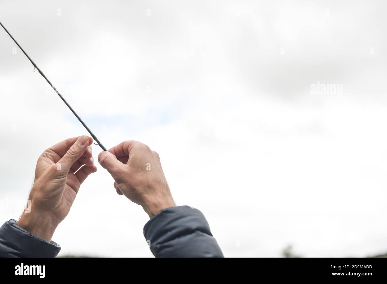 Male hands putting line on fishing rod Stock Photo - Alamy