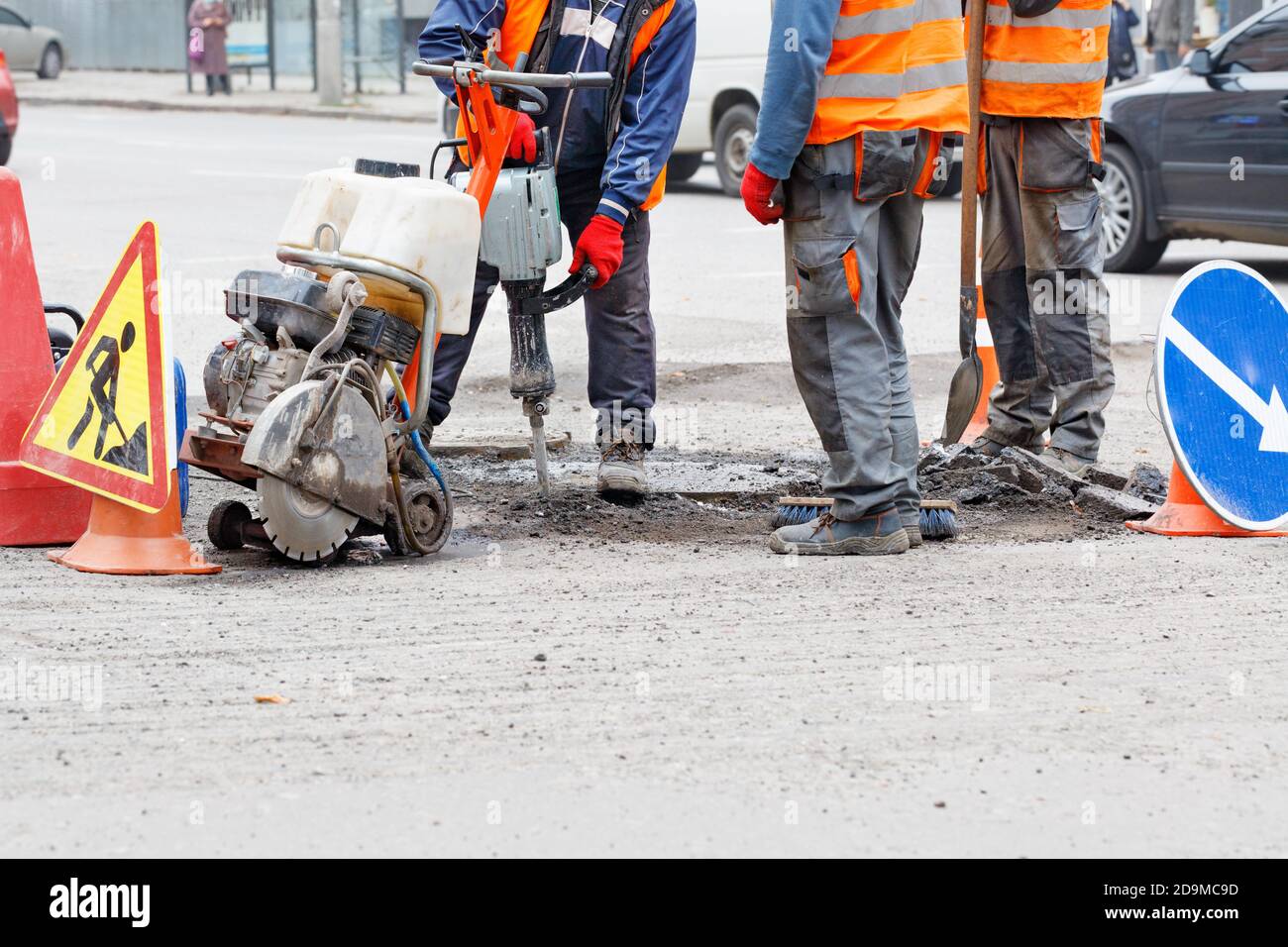 A team of road workers repairs a section of road with an electric ...
