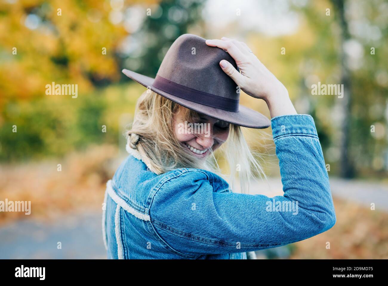 portrait of woman stood holding her hat that's blowing in the wind ...