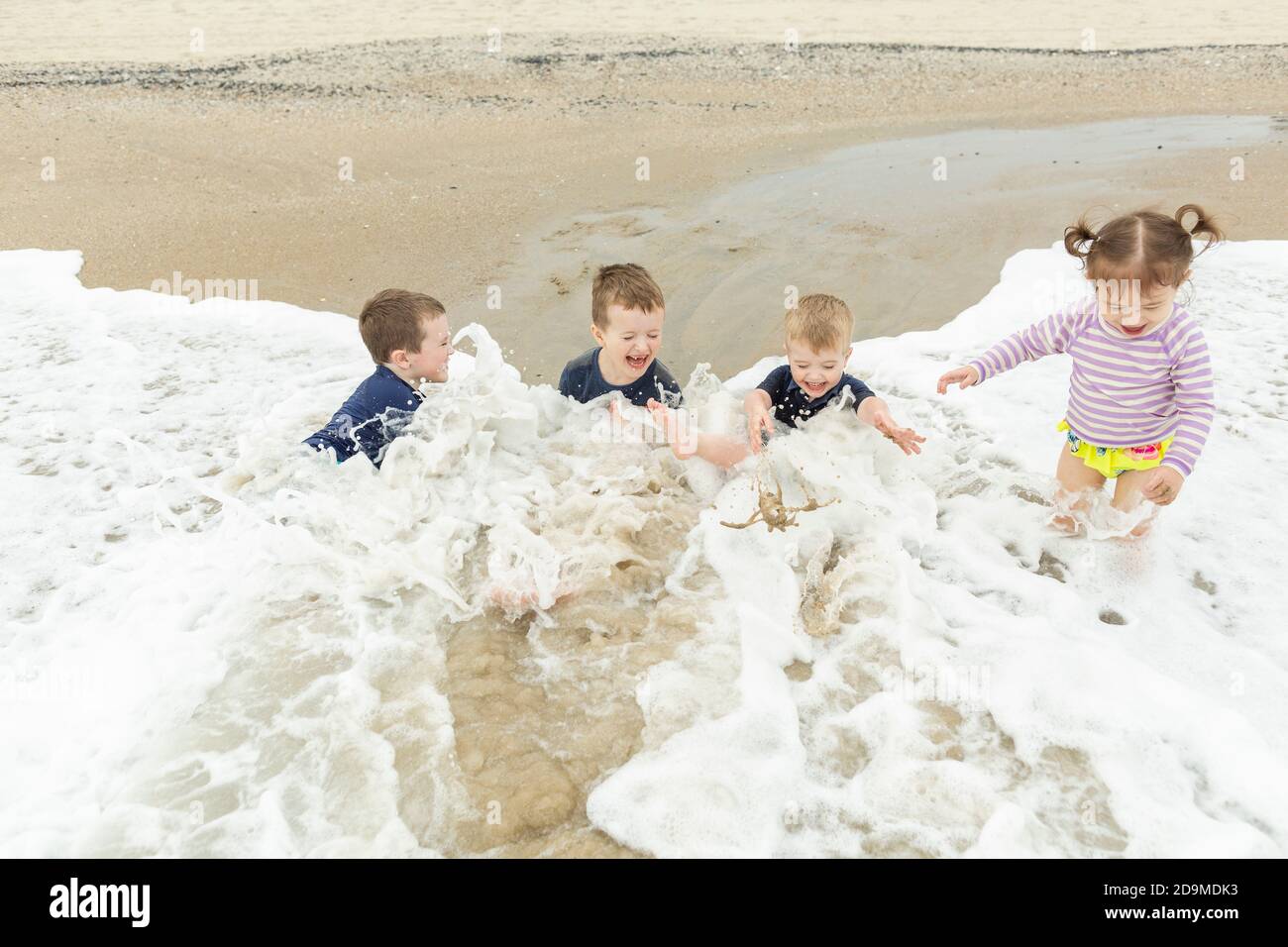 Happy Children Laughing As Waves Crash While Sitting at Edge of Ocean ...
