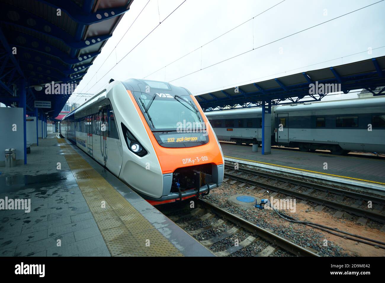 Passenger train standing on the railway track, empty platforms of the ...
